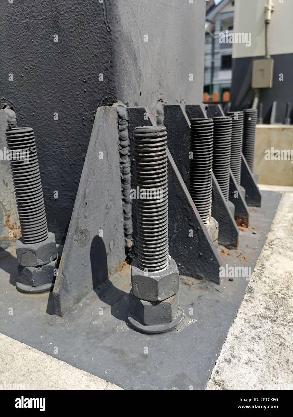 Bolts and nuts on the cement base. Several gray double bolts are firmly ...