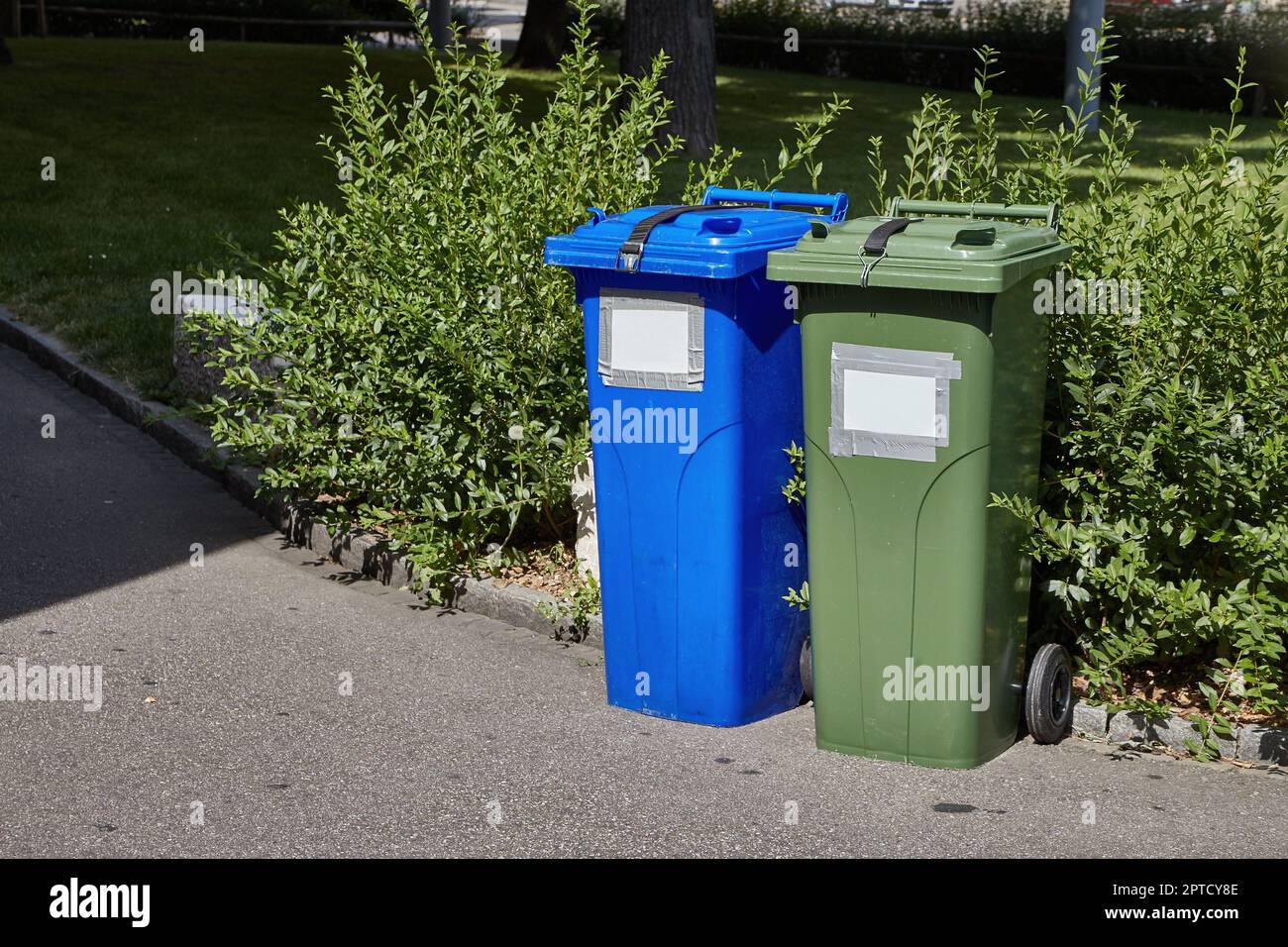 Trash containers for municipal waste on an green street Stock Photo - Alamy