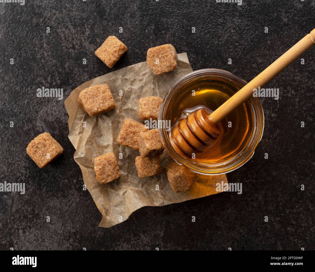 Brown sugar with honey and wooden honey dipper on stone background ...