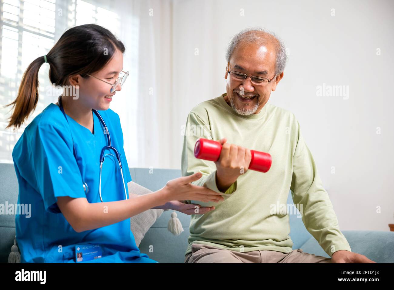 Asian nurse physiotherapist helping senior man in lifting dumbell at retirement home, Young ...