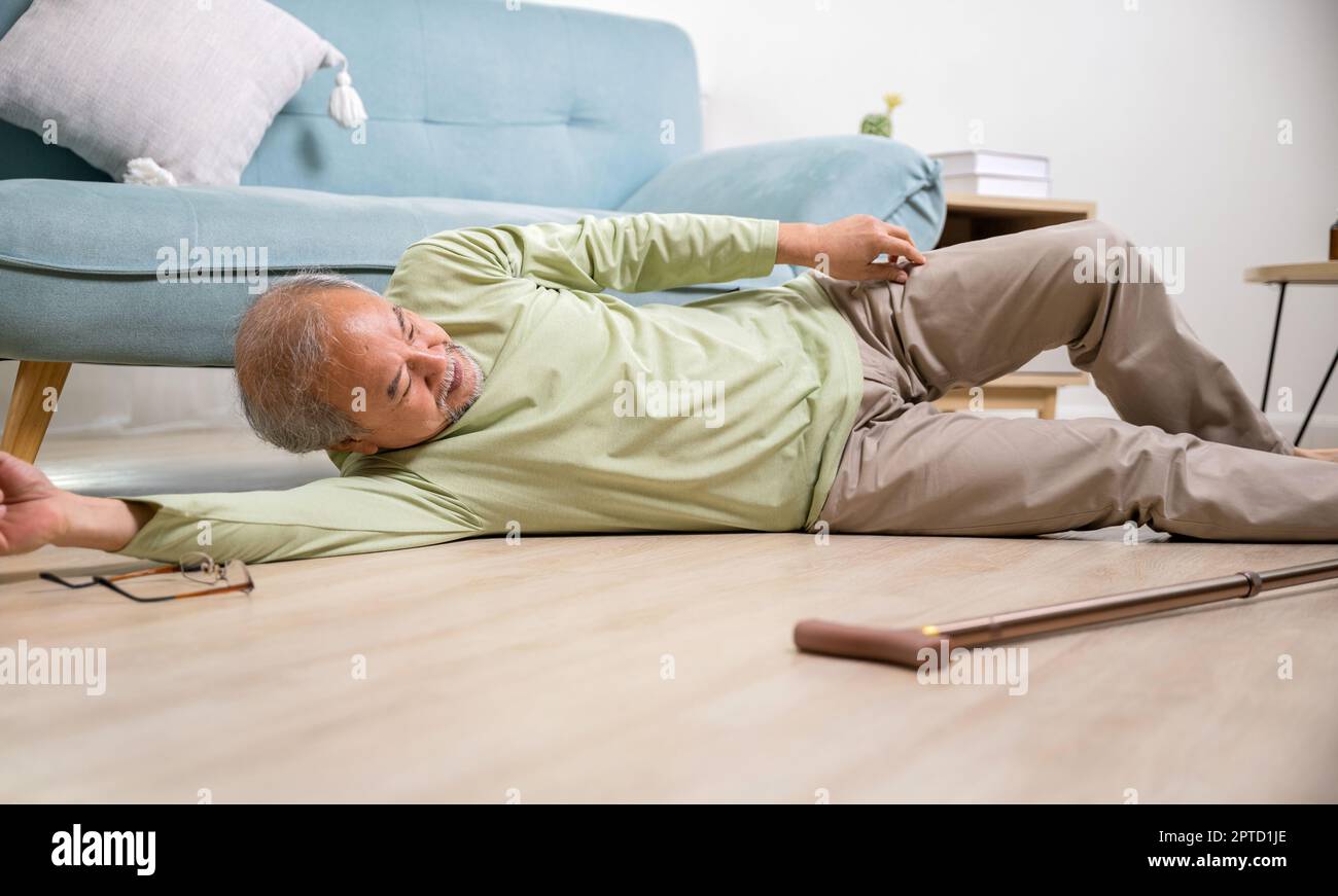 Asian old man lying on floor after falling down with wooden walking ...