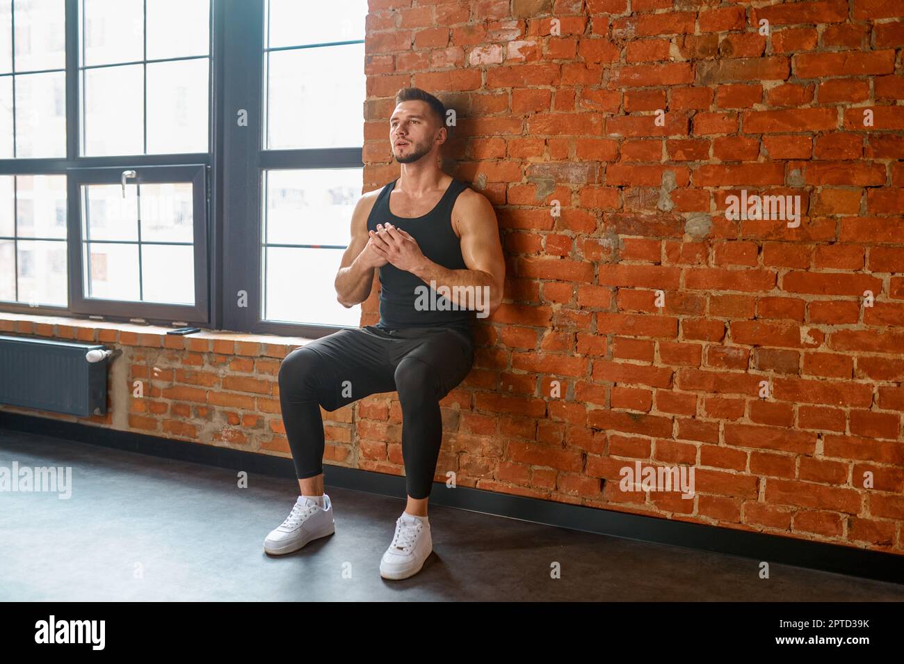 Athlete doing training exercise against gym wall. Sportsman exercising ...