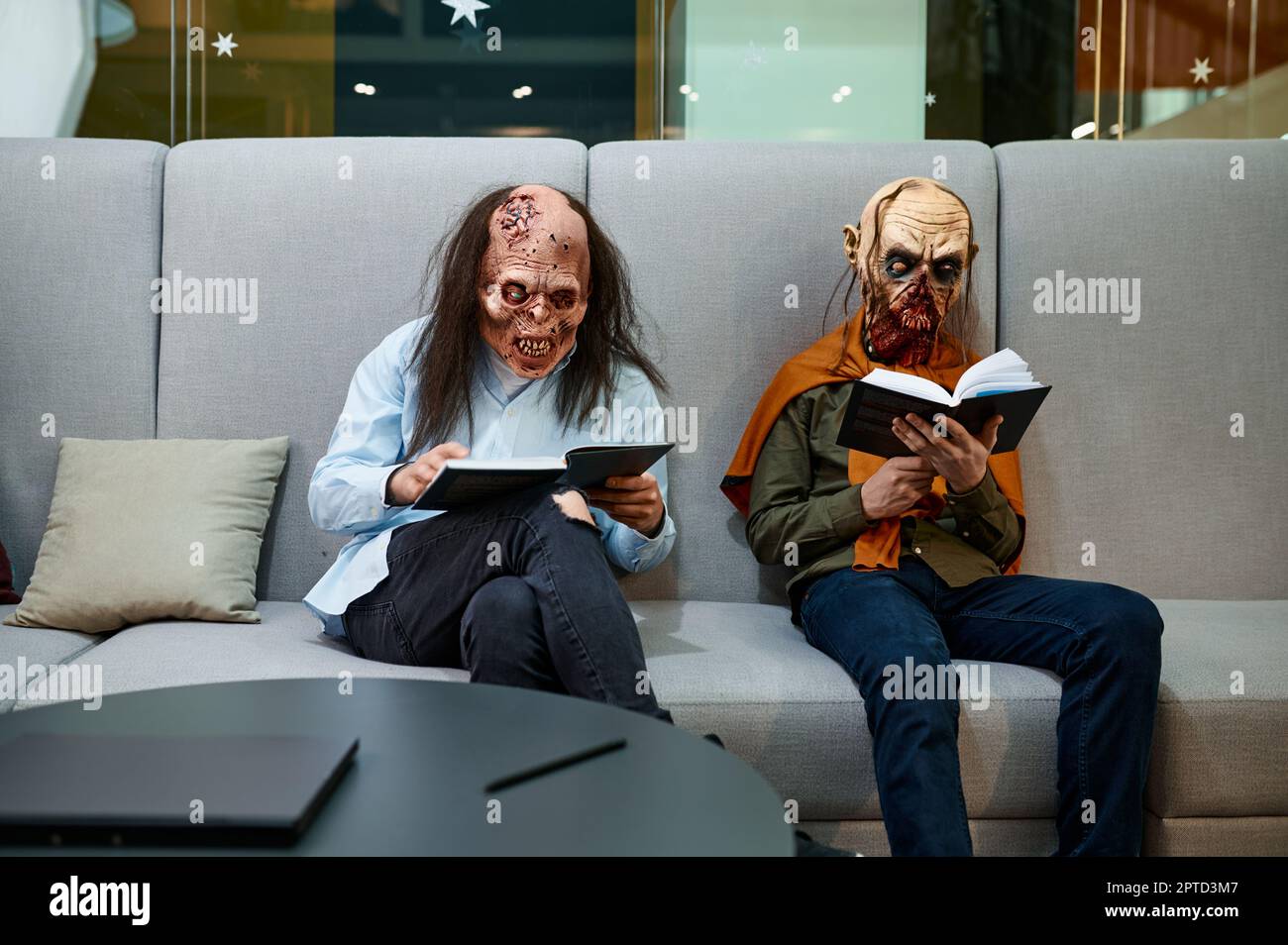 Zombie employees reading books during work break sitting on sofa in ...