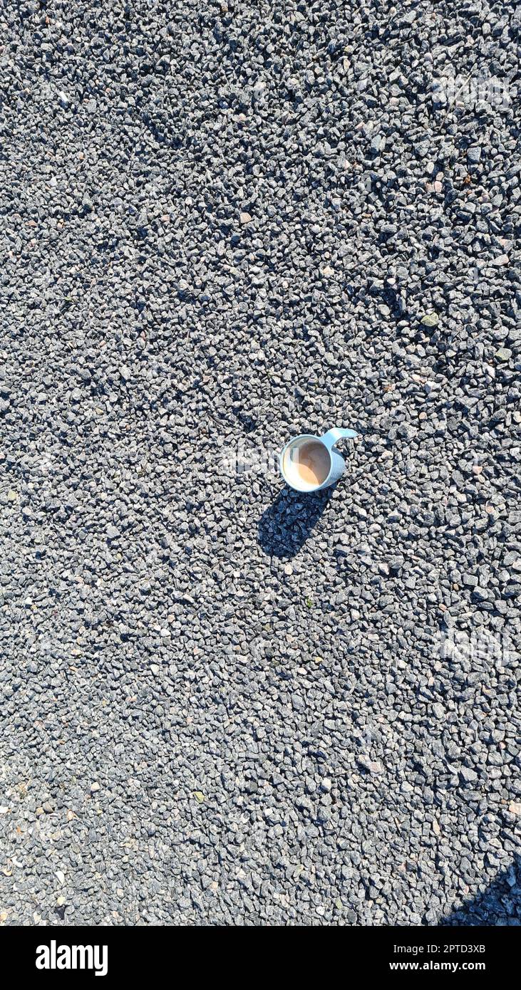Blue coffee cup with fresh coffee stands on the floor, surrounded by ...