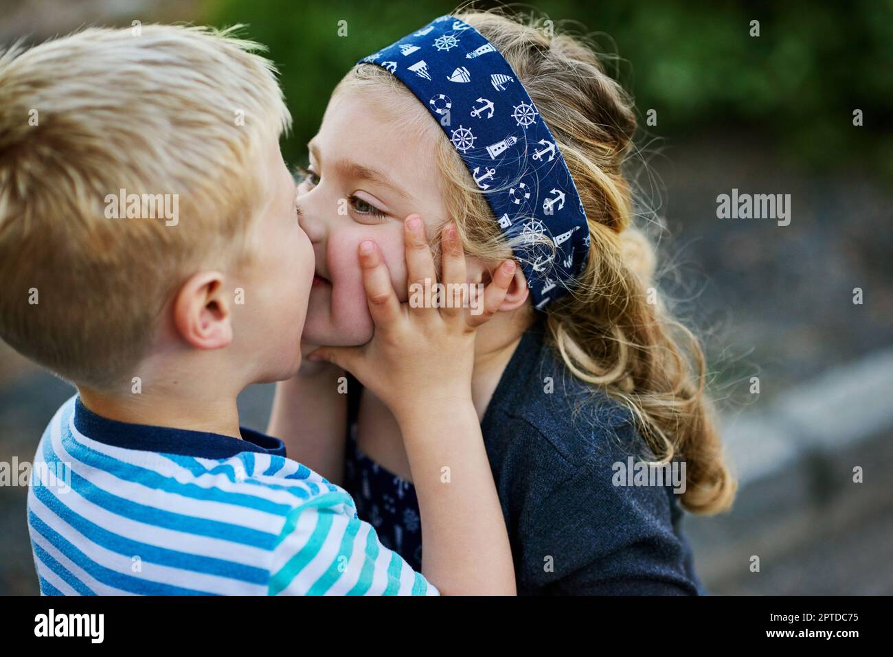 Theyre not afraid to show a little affection. a little girl giving her brother a kiss while they ...