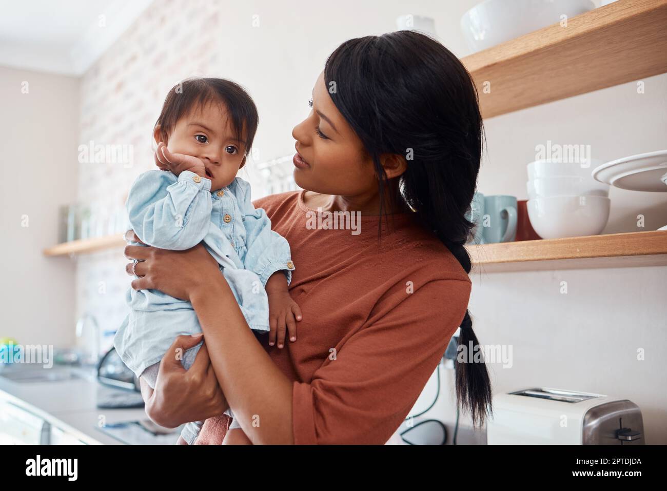 Love, down syndrome and mother and baby in a kitchen, embrace and ...