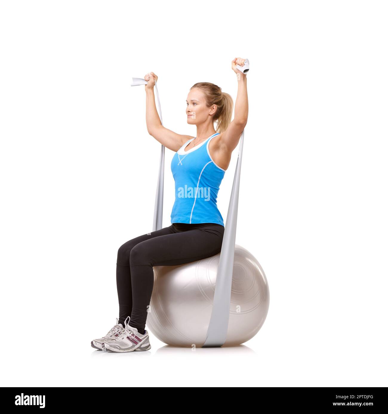 Exercising her entire body. A young woman sitting on an exercise ball ...
