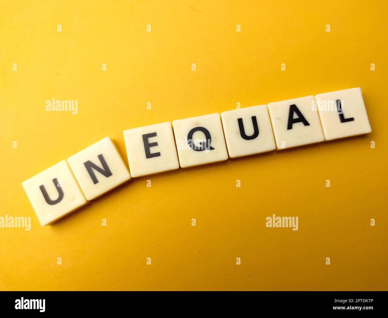 Toy word with the word UNEQUAL on yellow background Stock Photo - Alamy
