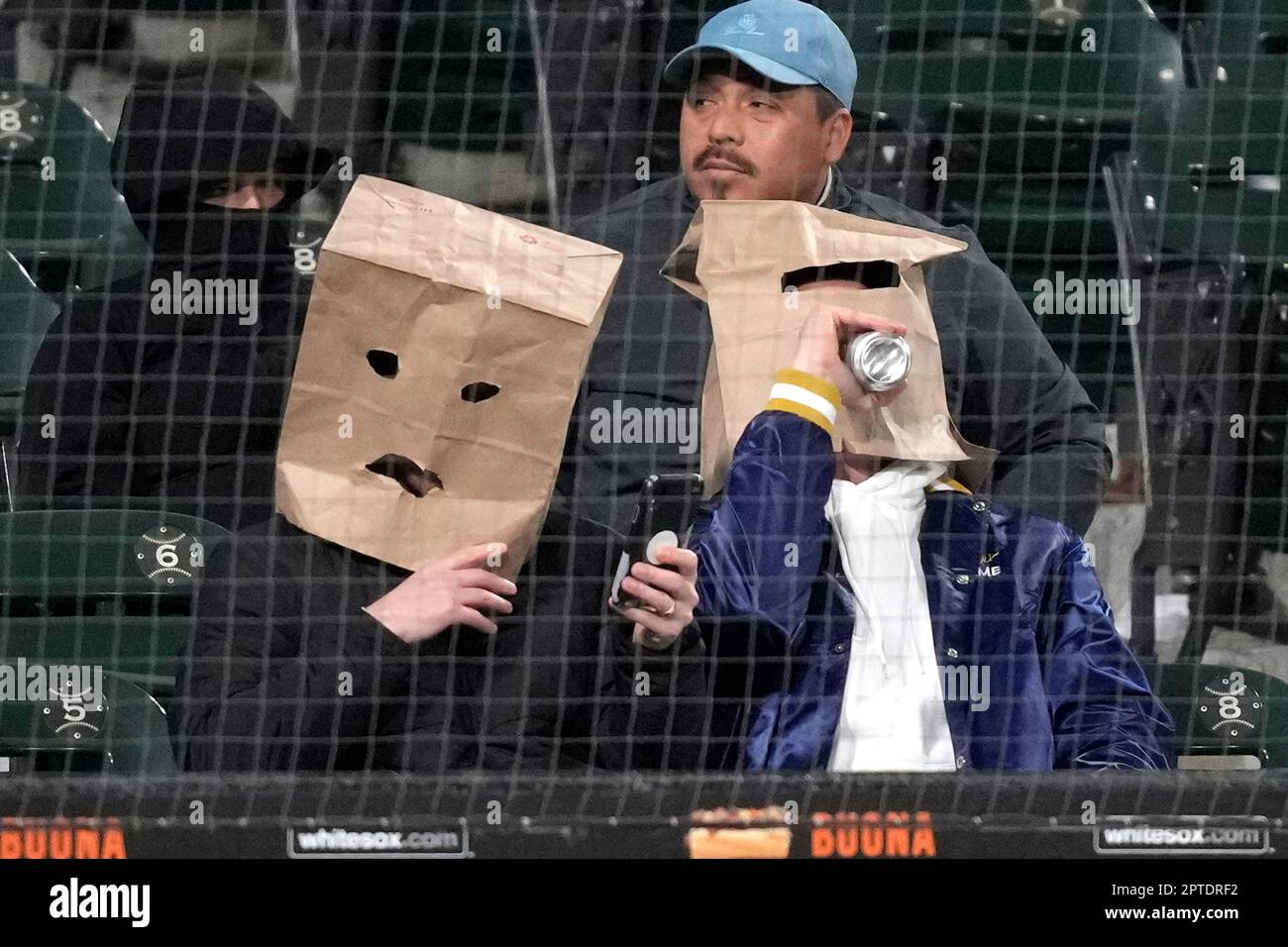 Two fans wear paper bags on their heads during the eighth inning of a ...