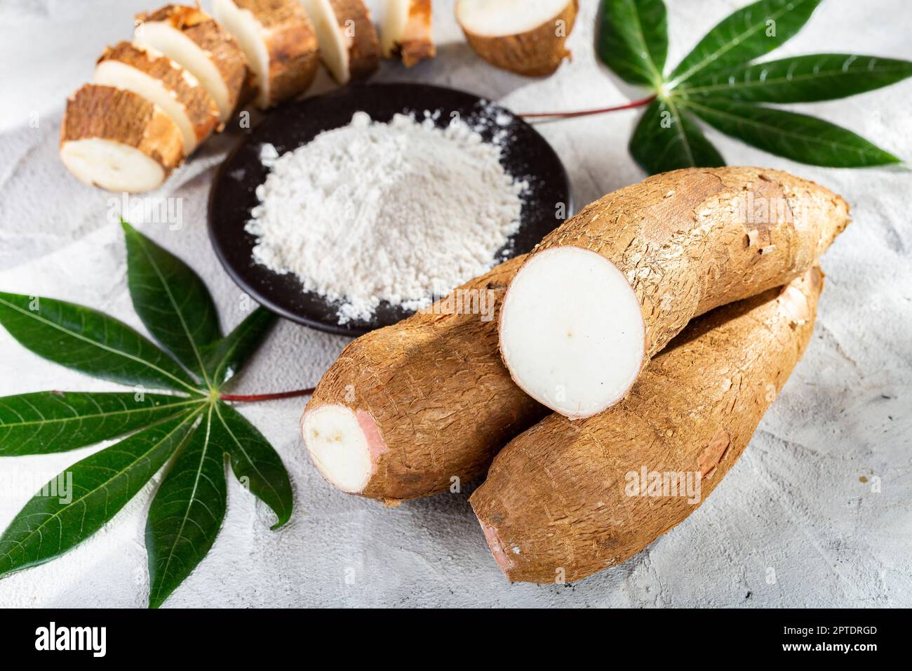 pile of cassava root and cassava flour on a gray and white textured ...