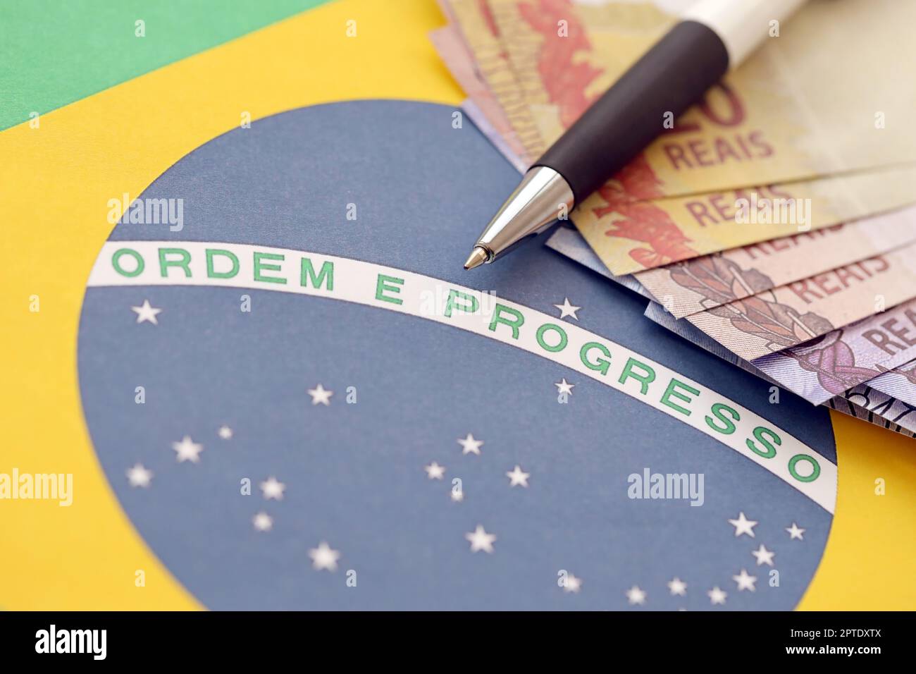 Pen with Brazilian money bills on flag of Brazil republic. Concept of ...