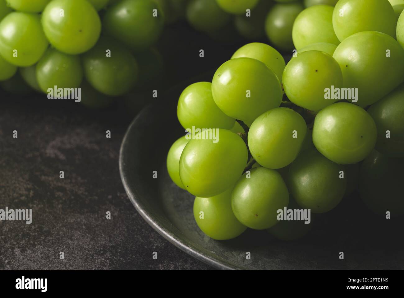 Shine Muscat placed on an iron plate against a black background. White ...