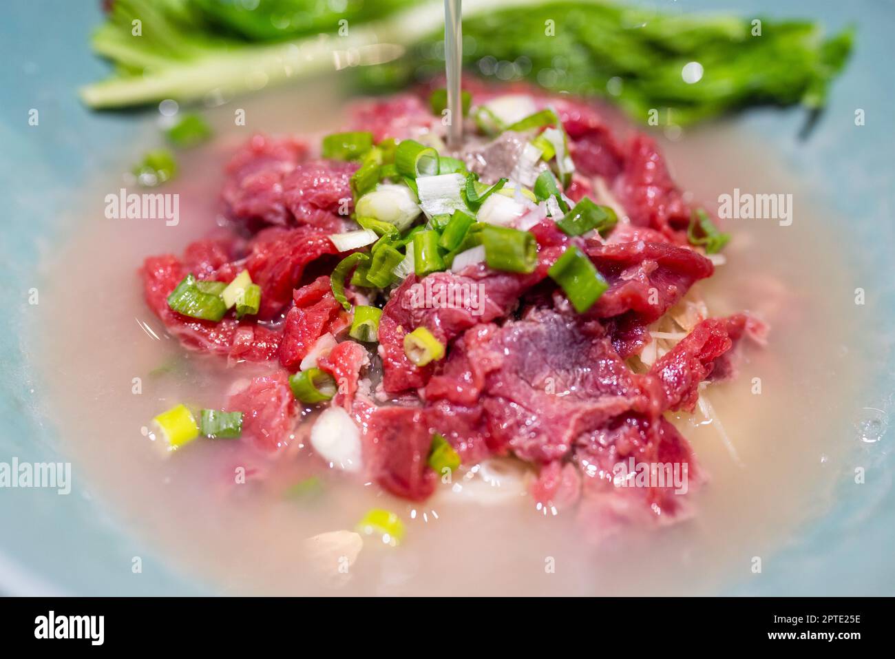 Boiling hot soup pour into noodle with slice of raw beef, famous ...