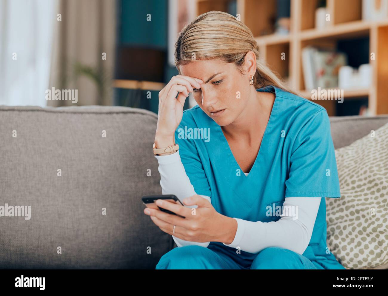 Phone, healthcare and worry with a woman nurse reading a text message ...