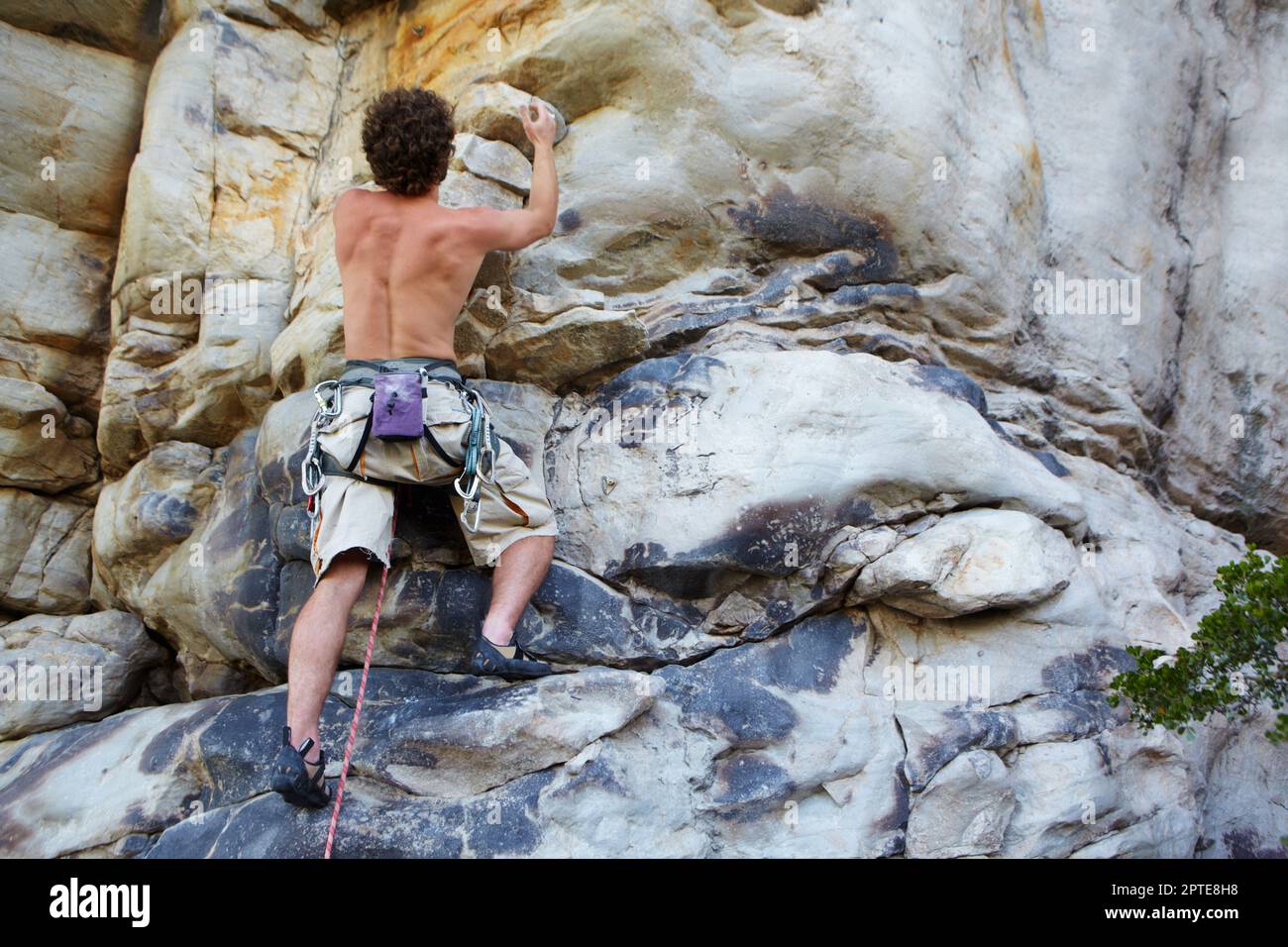 Making sure that its stable. A rock climber trying to get a grip on the ...