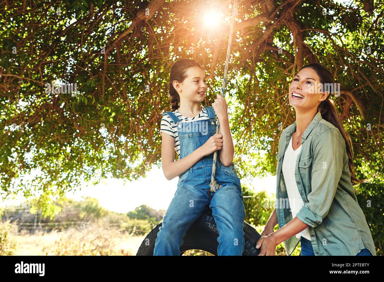 Summertime fun in full swing. a mother pushing her daughter on a swing at the park Stock Photo ...