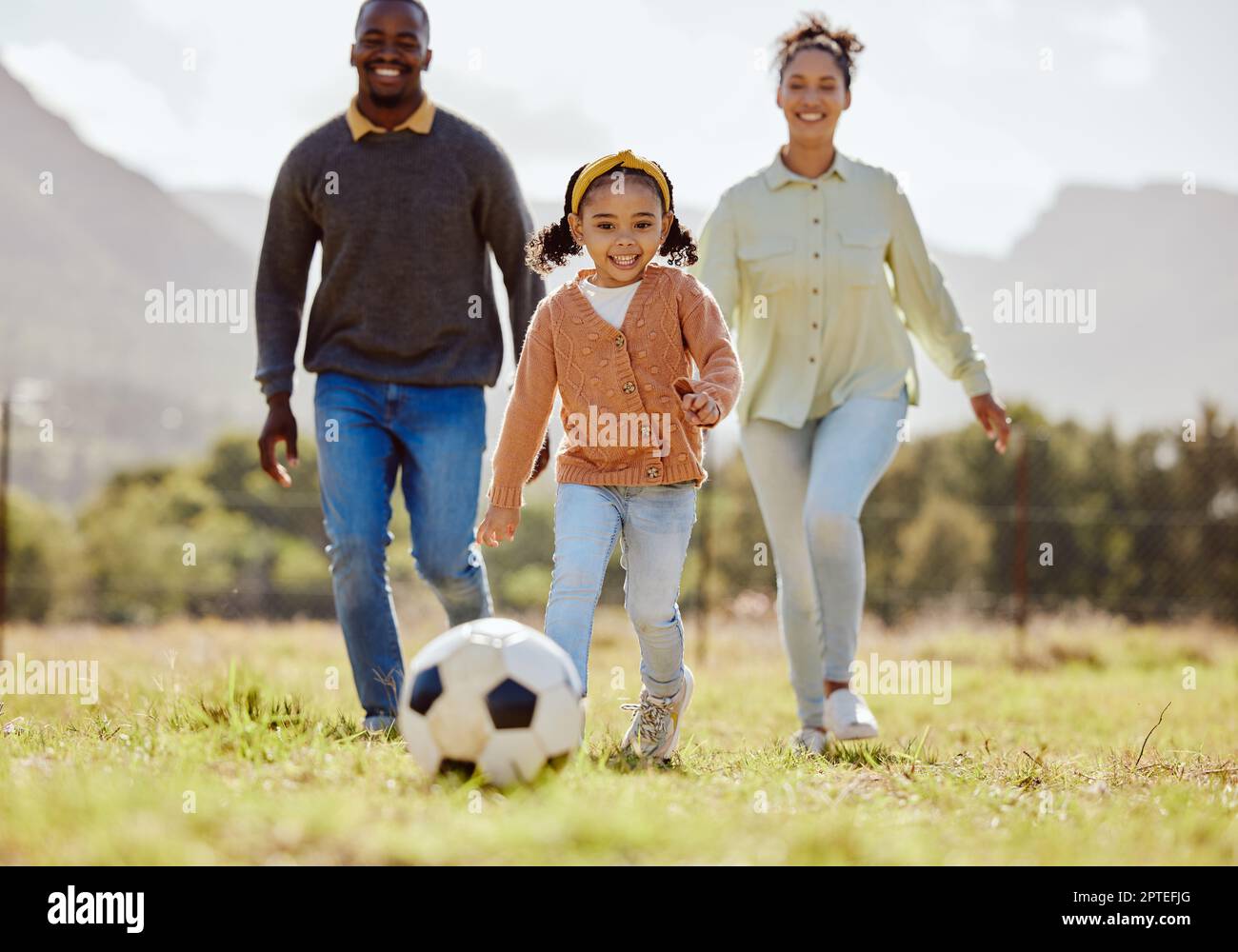 Happy family, soccer ball and playing on the grass in nature for fun ...