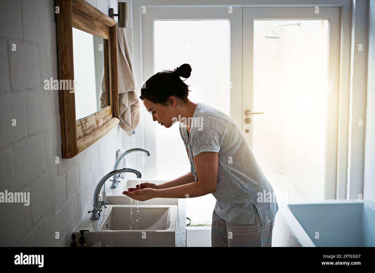 Getting refreshed. an attractive young woman washing in the bathroom ...