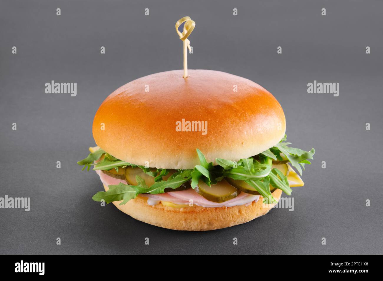 Simple burger with ham, pickled cucumber, arugula and soft cheese Stock ...