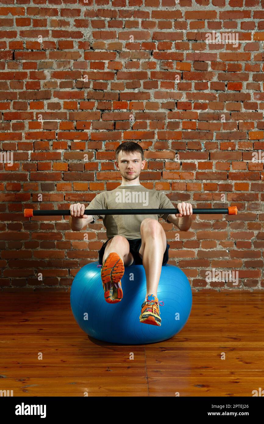 Athletic man doing exercises for the balance on rubber ball with ...