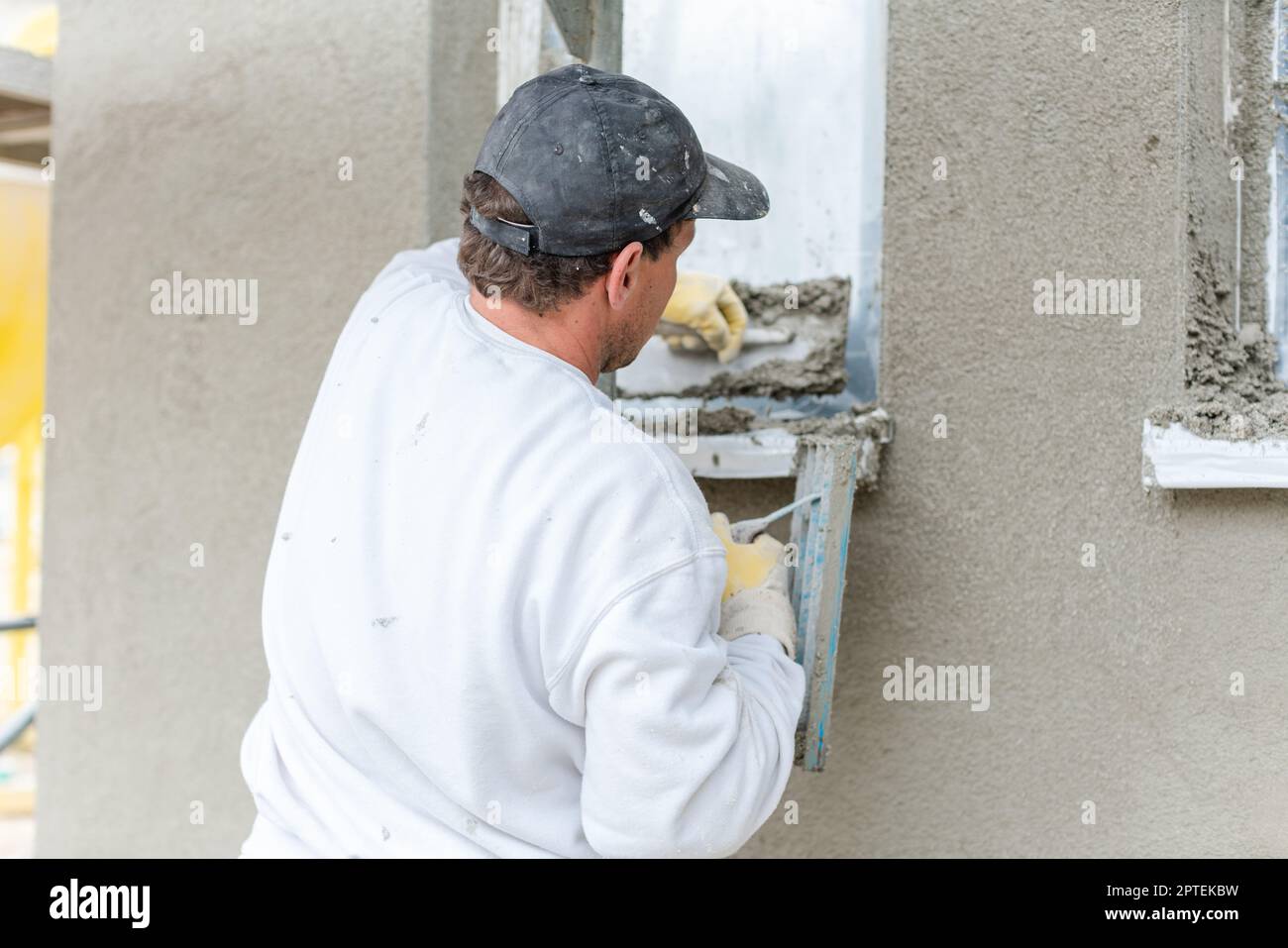 Plasterer smoothing plaster on a facade standing on scaffold Stock ...