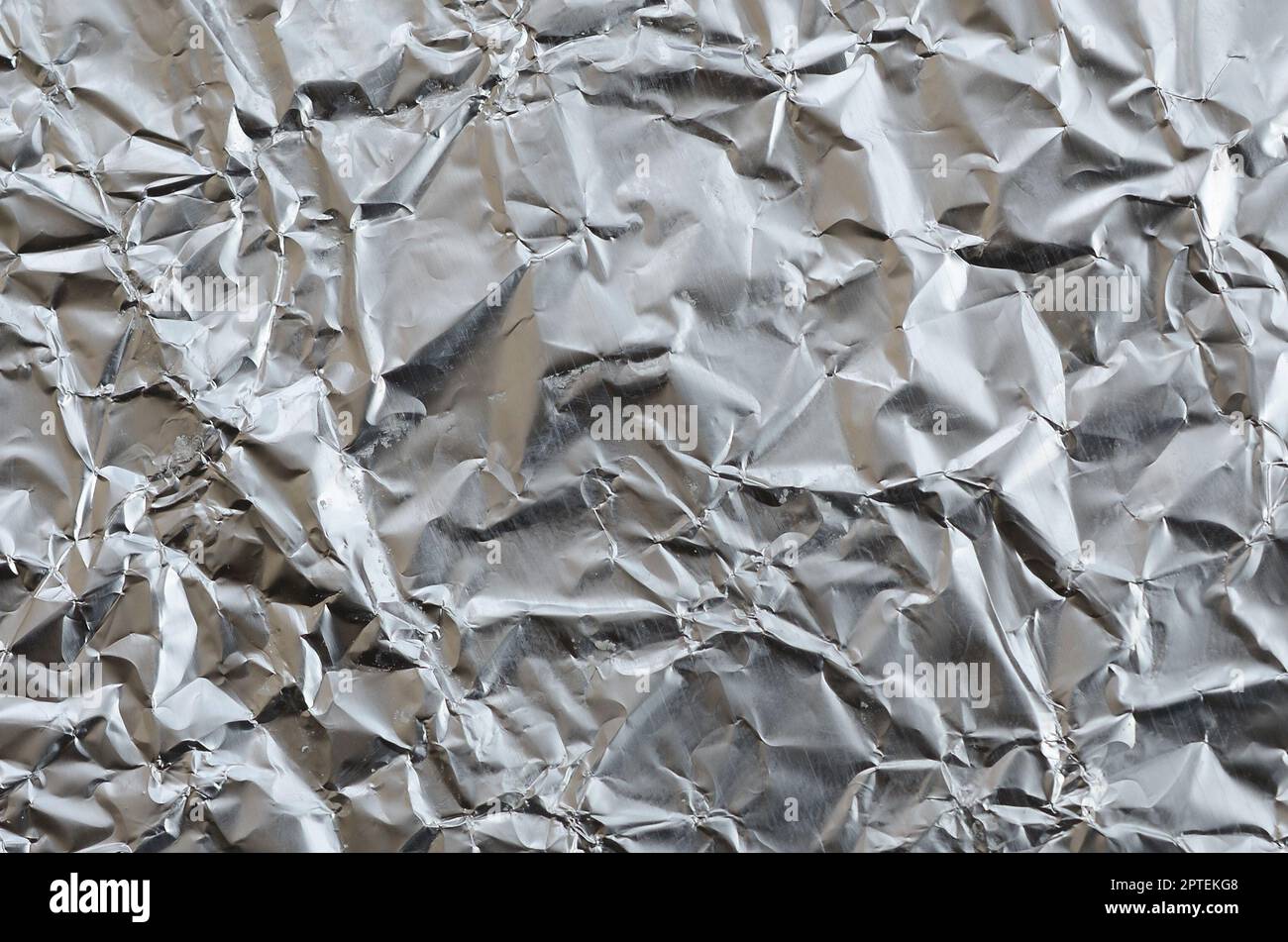 Thin wrinkled sheet of crushed tin aluminum silver foil background with ...