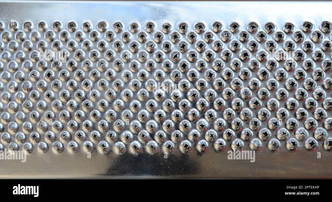 A fragment of a metal chrome grater close-up. Texture of blades for ...