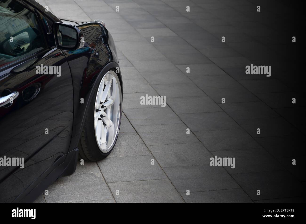 Diagonal view of a black glossy car with white wheels, which stands on ...