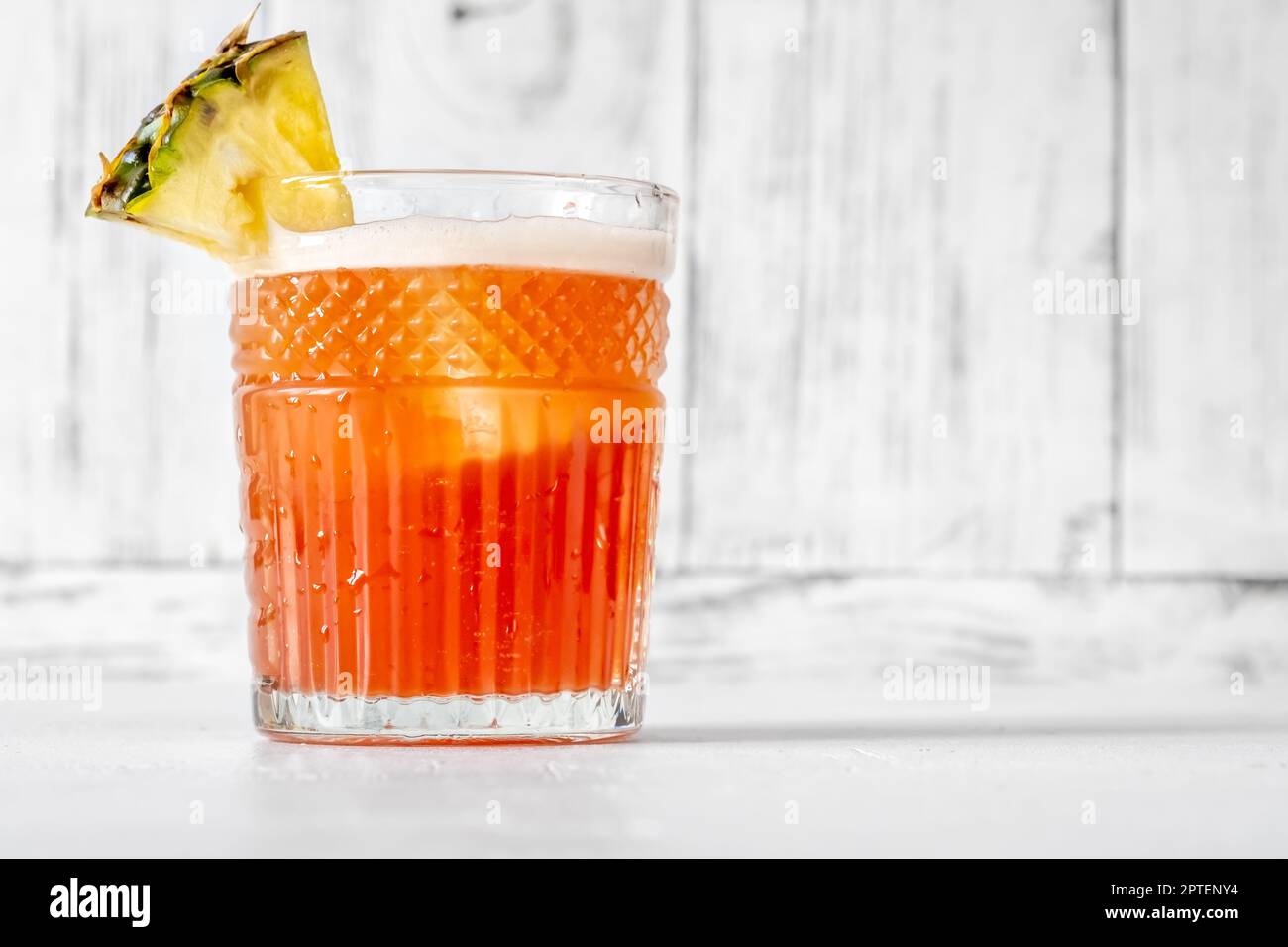 Glass of Jungle Bird cocktail garnished with pineapple wedge Stock ...