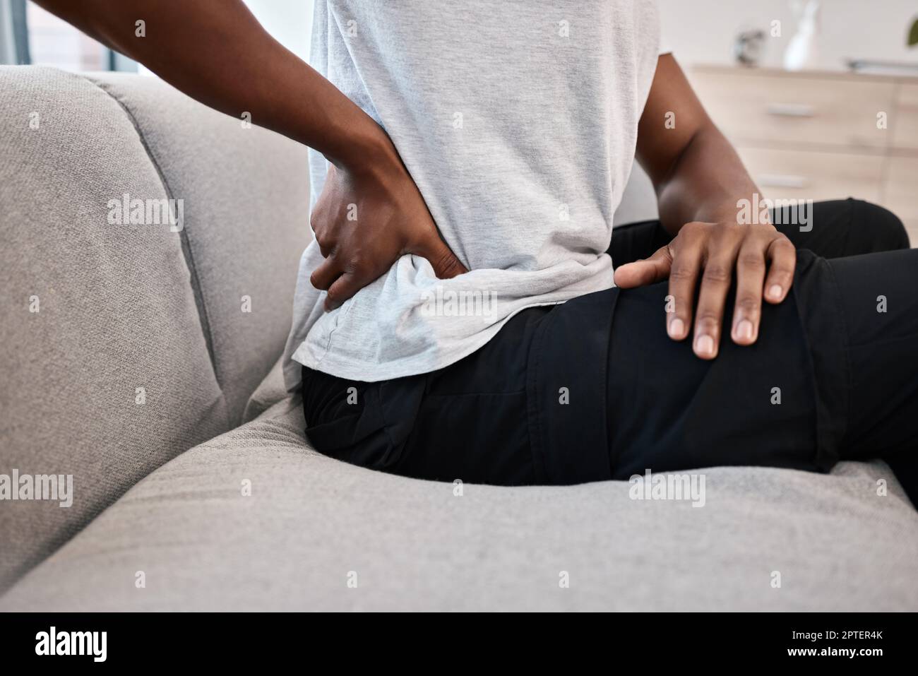 hand, back pain and woman at home on the couch after injury or accident ...