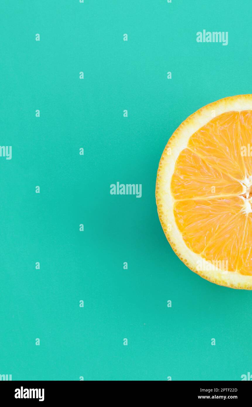 Top view of a one orange fruit slice on bright background in turquoise ...