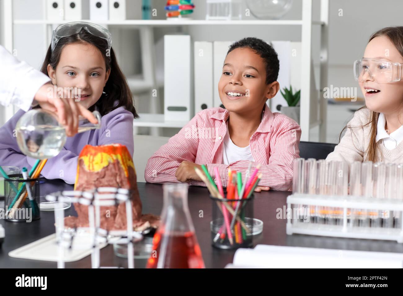 Little children having experiment with teacher and chemical volcano in ...