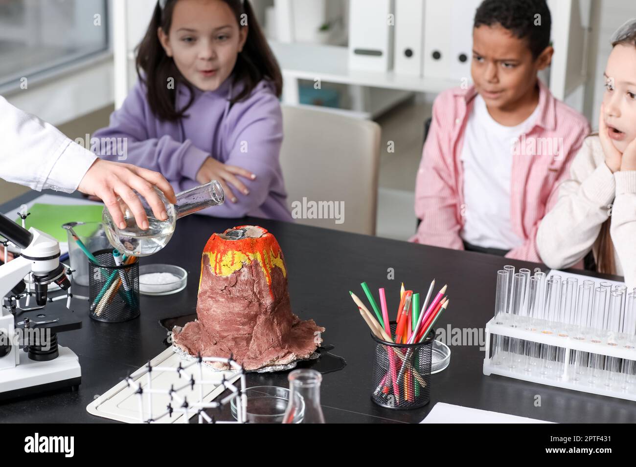 Teacher making experiment with chemical volcano for little children in ...