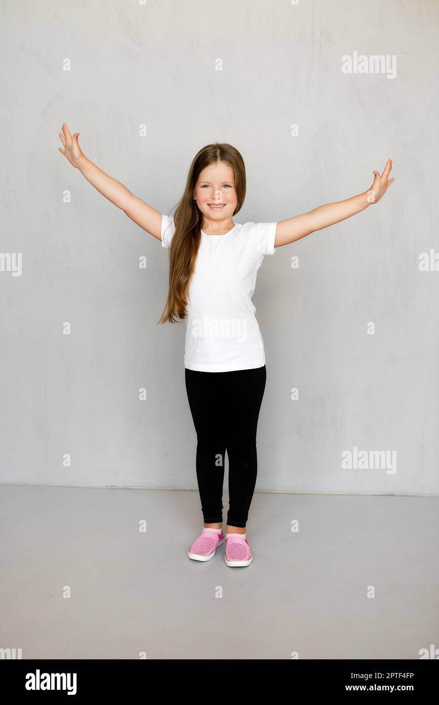 Cute young child with long hair in t-shirt and sweatpants standing with ...