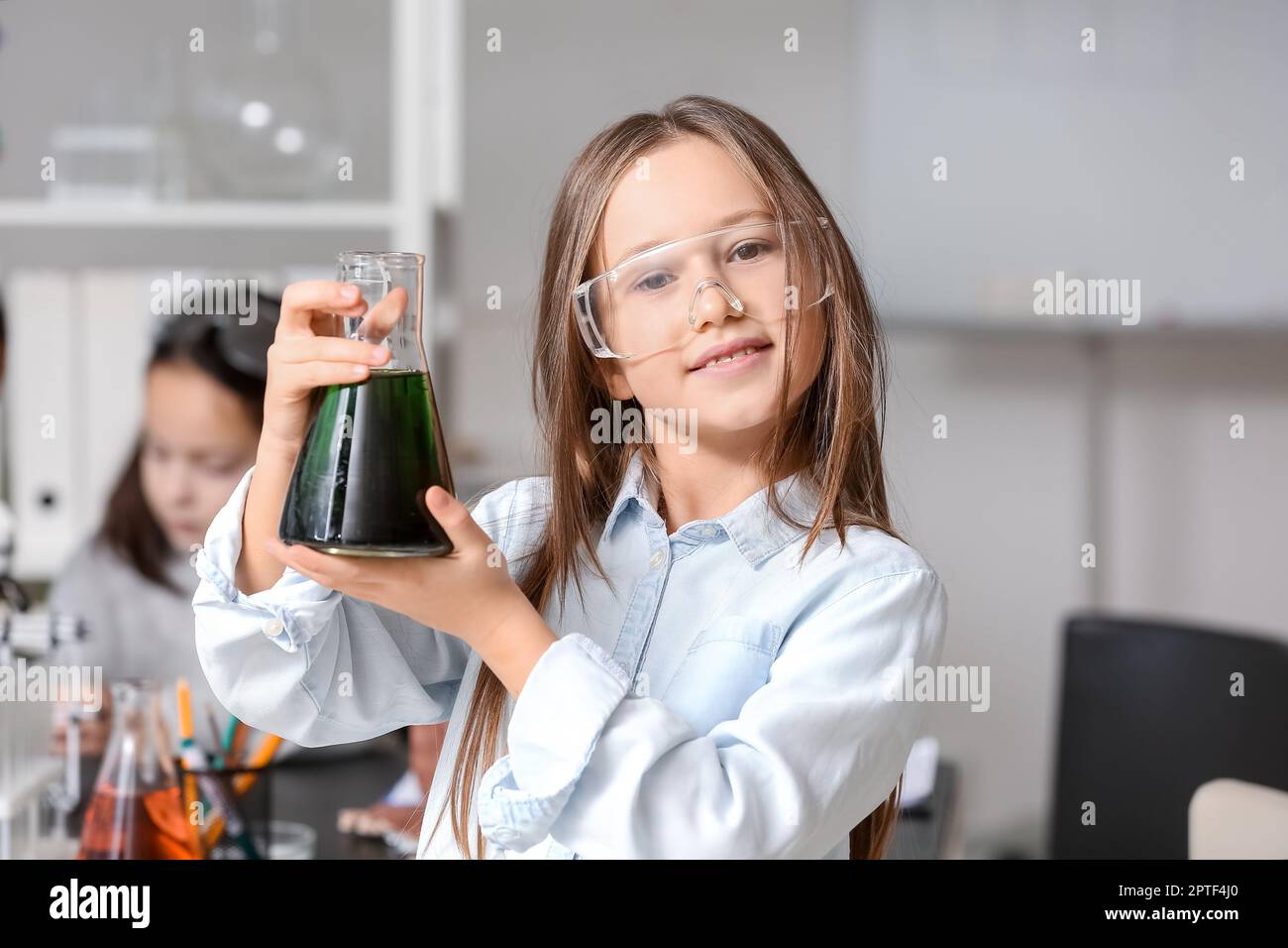 Little girl with conical flask in science classroom Stock Photo - Alamy