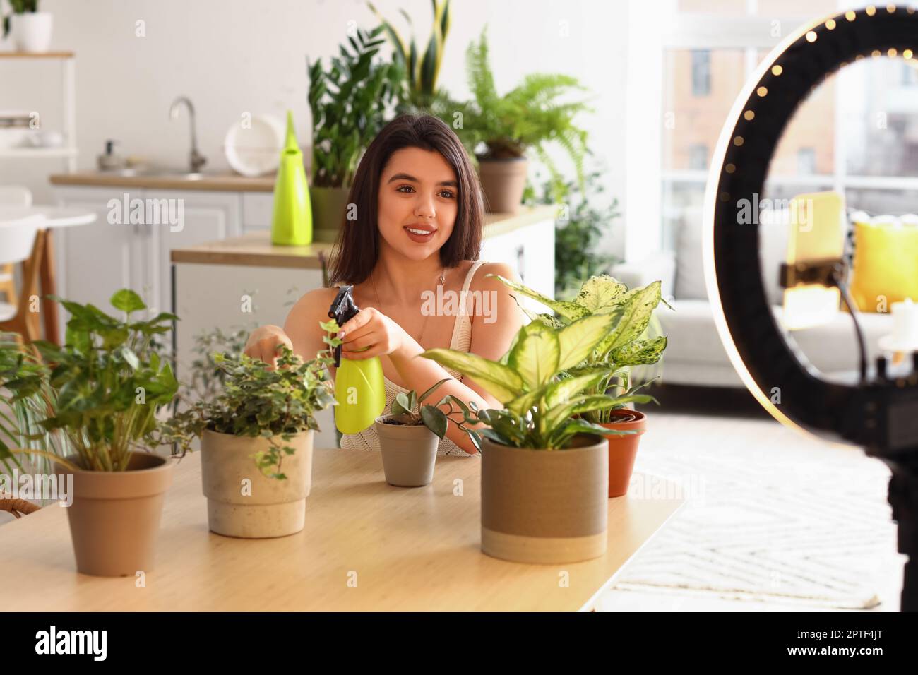 Female blogger with houseplant taking video at home Stock Photo - Alamy