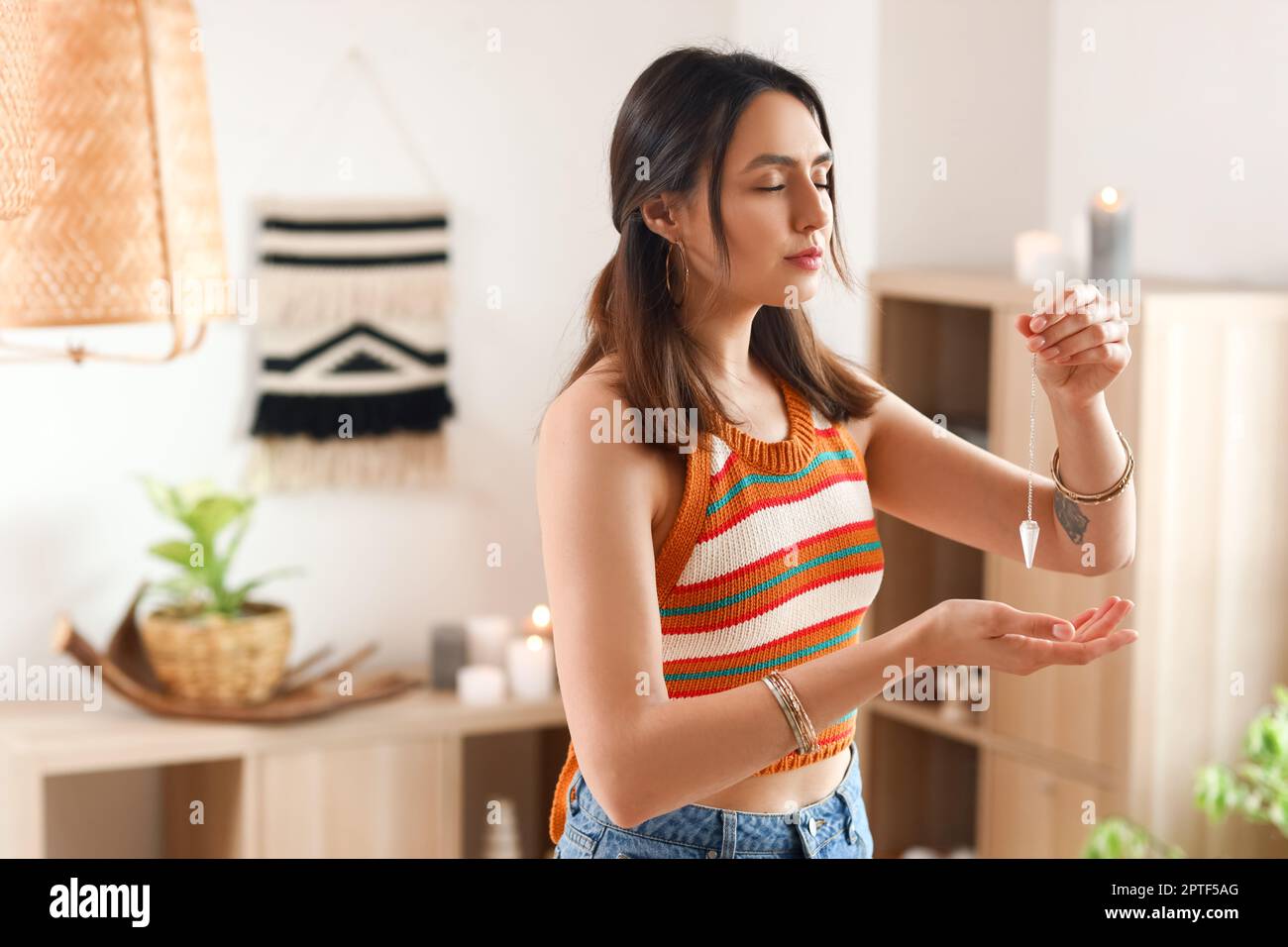Young woman with pendulum at home Stock Photo - Alamy