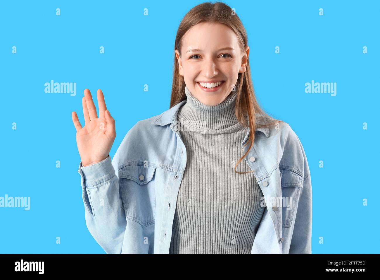 Female student waving hand on blue background Stock Photo - Alamy
