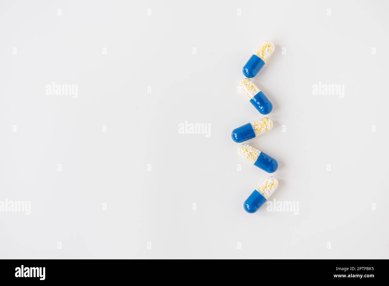Medical pills-capsules, half blue on a white background, lying in a row ...