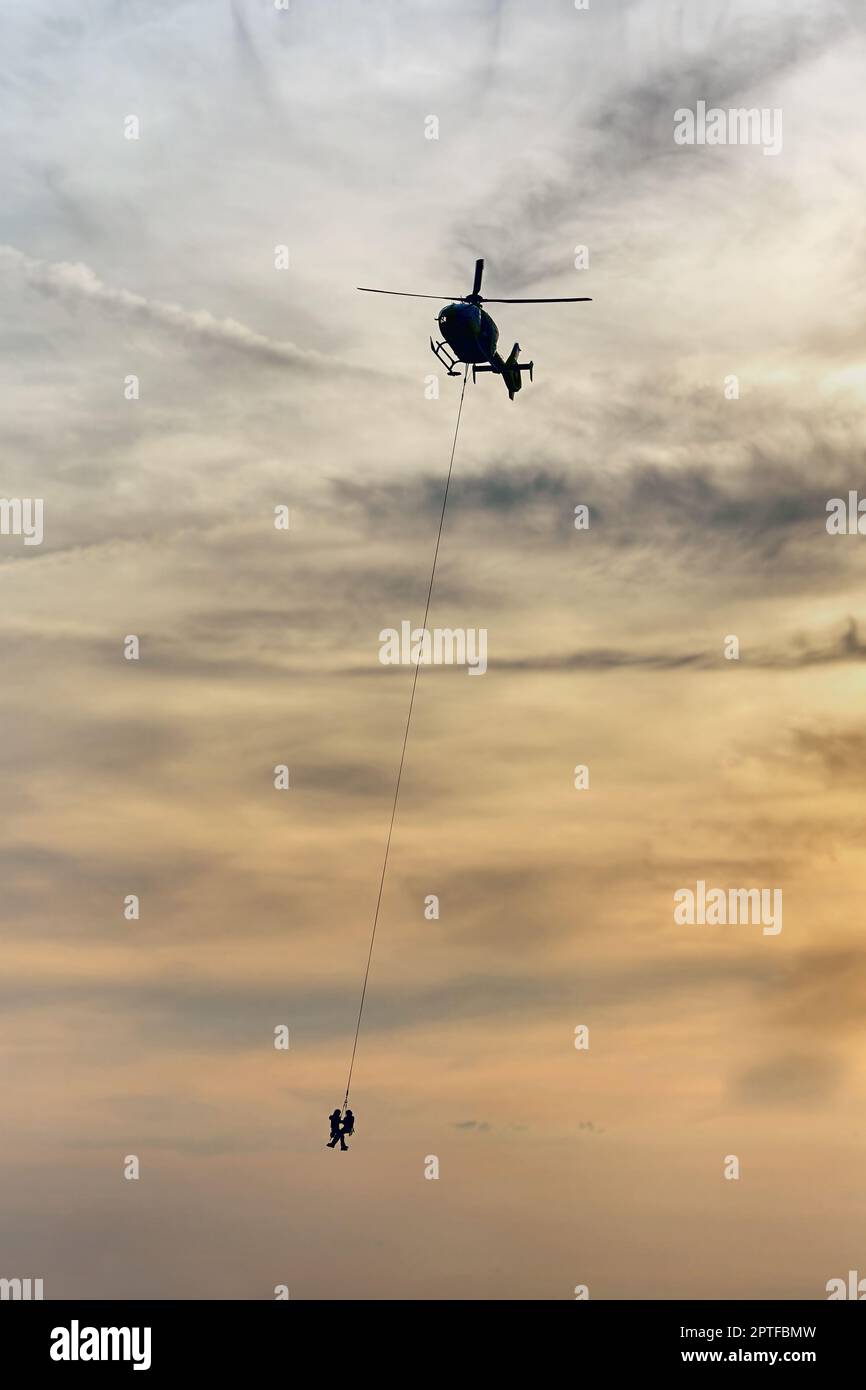 Rescue helicopter flying with people hanging from a rope Stock Photo ...