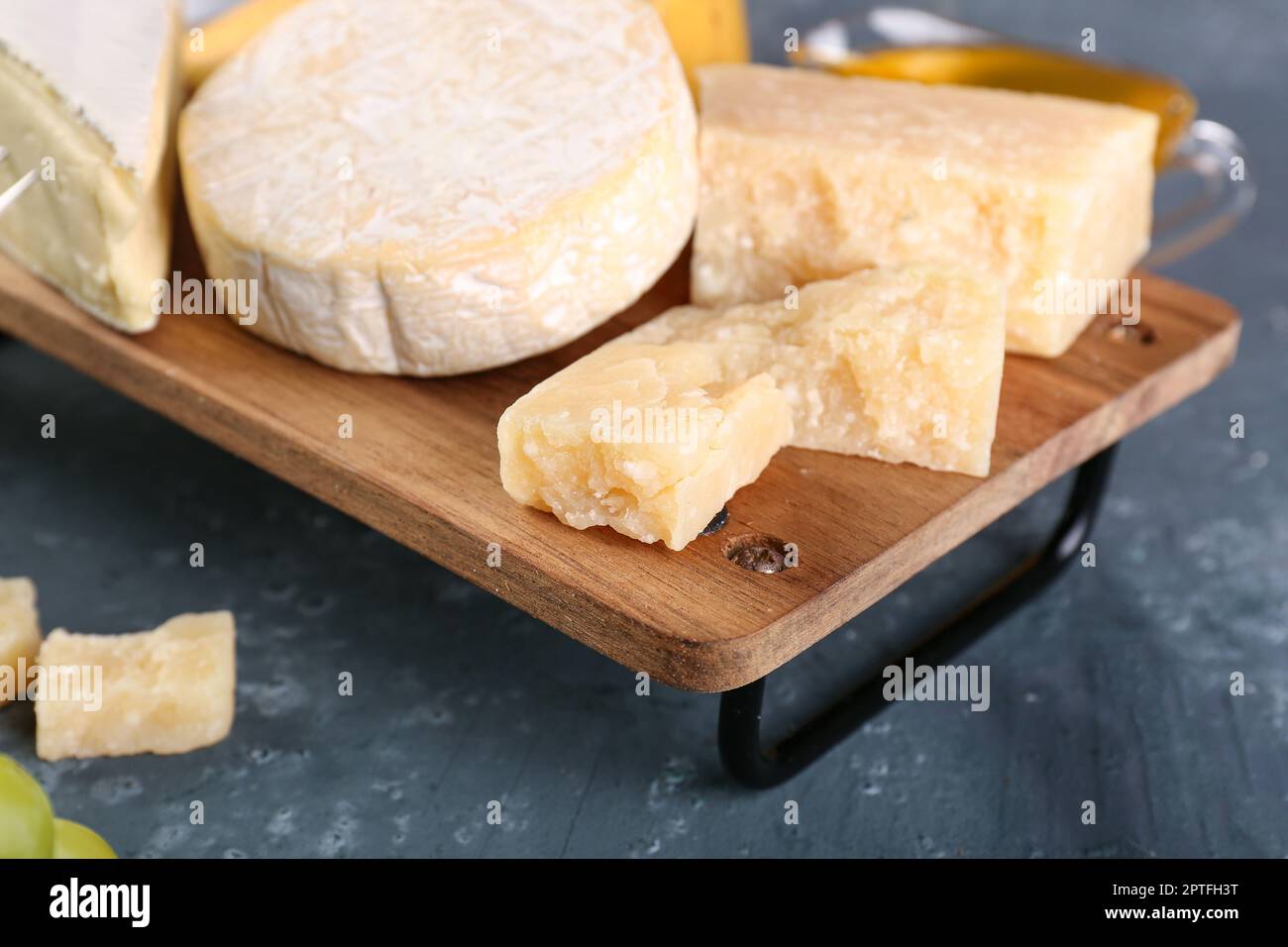 Wooden board with different types of cheese on green background ...