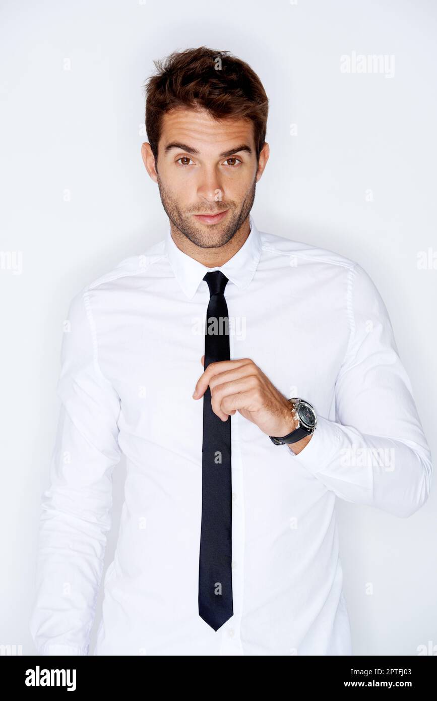 Looking sharp. Handsome young guy adjusting his tie against a white ...