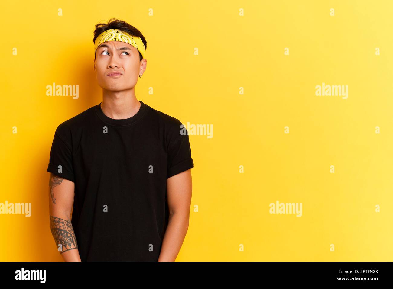 Portrait of Asian man in black Tshirt and and yellow headband holding ...