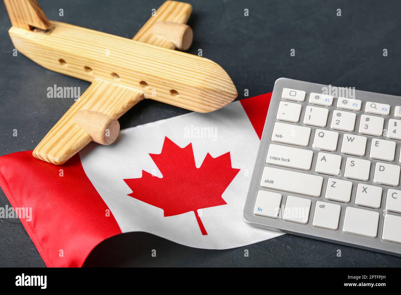 Flag of Canada with wooden airplane and computer keyboard on dark ...