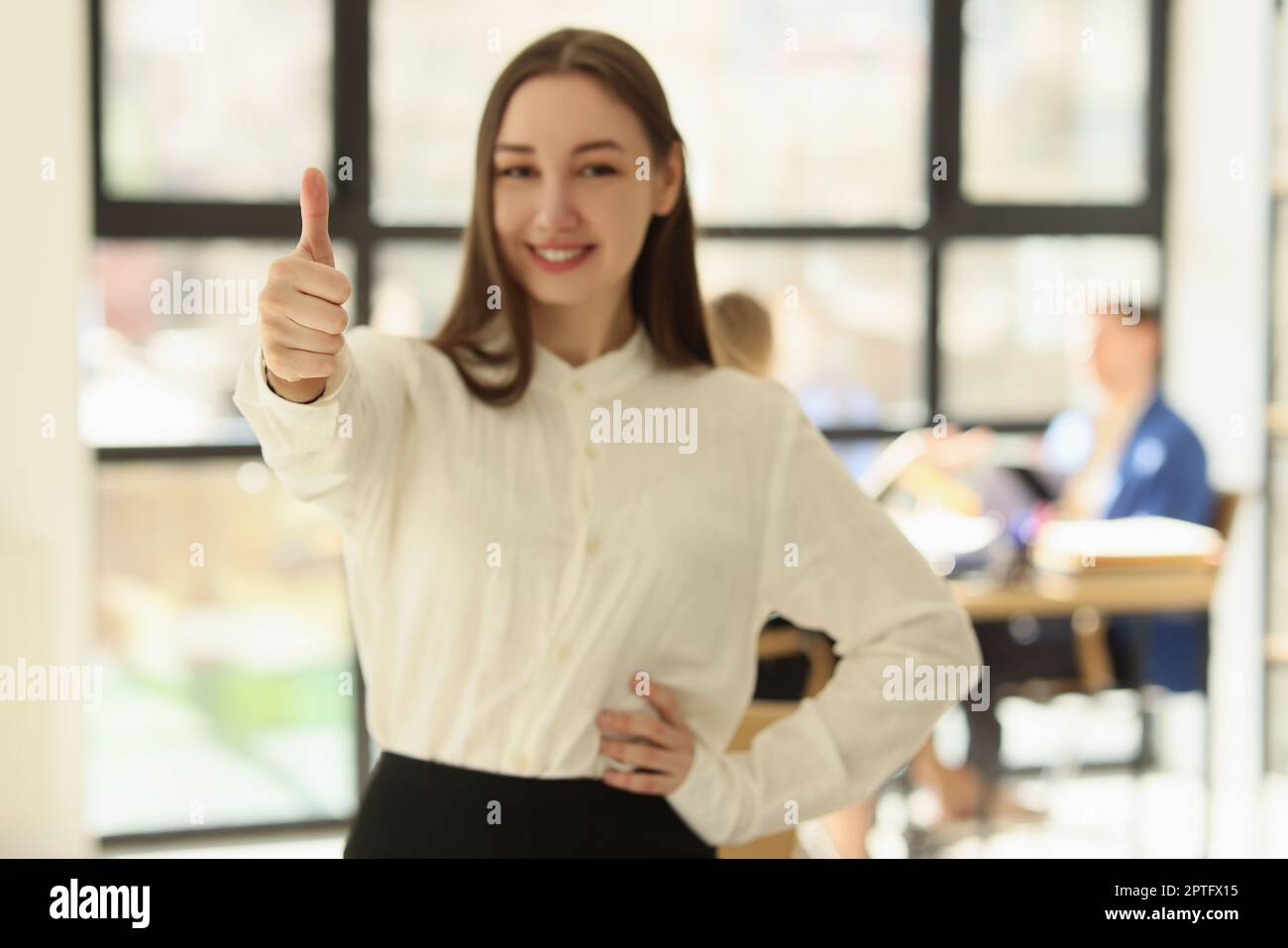Cheerful young woman in formal outfit shows thumb up smiling Stock ...