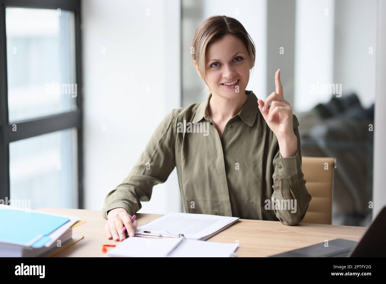 Positive woman points index finger up looking in camera Stock Photo - Alamy