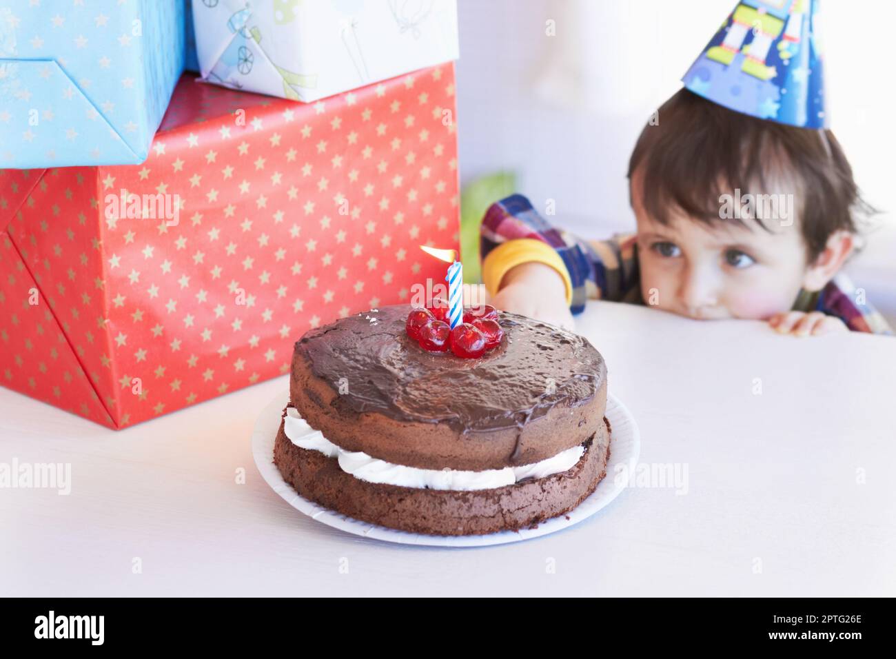 Cant wait to eat his cake. A cute little boy looking at his birthday ...