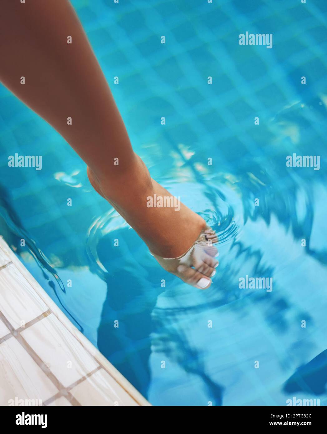 Welcoming waters. a woman dipping her feet in the water of a pool Stock ...