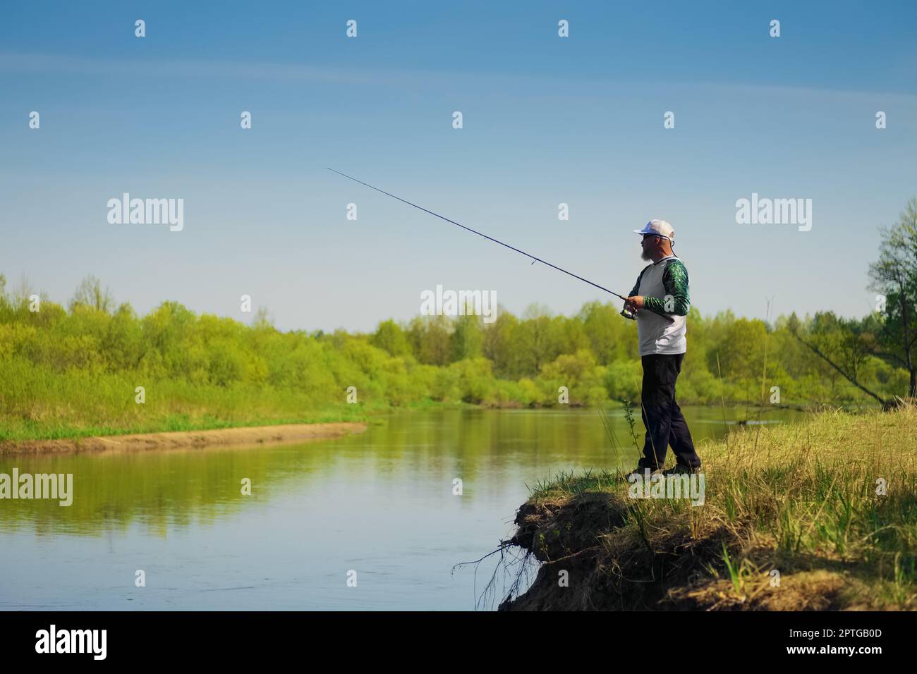 Fisherman with a spinning rod catching fish on a river at sunny summer ...