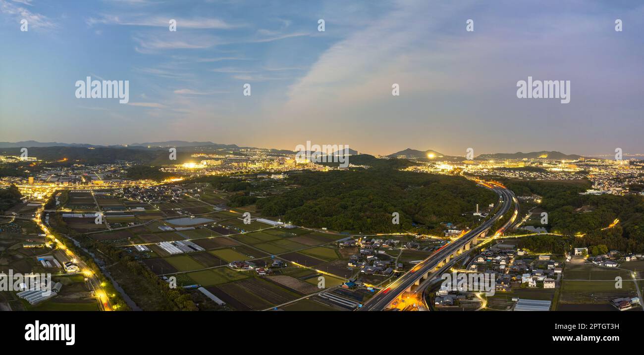 Sunset glow and lights from country roads by rice fields at edge of ...